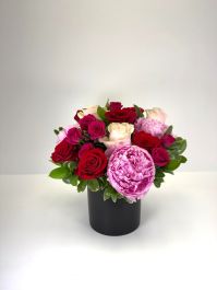 Cupids Arrow has Roses and Peonies in Reds and Pinks